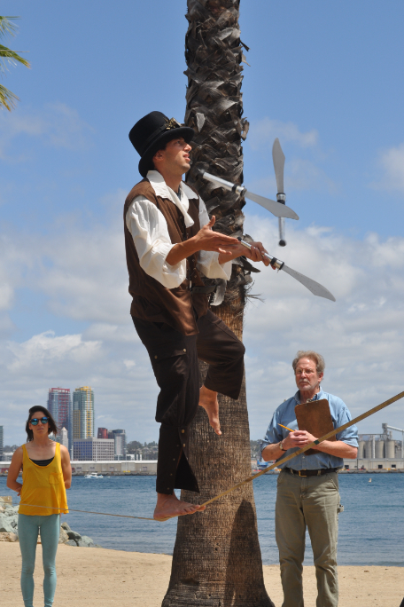 Daring circus performer juggles knives while walking a slackline ...