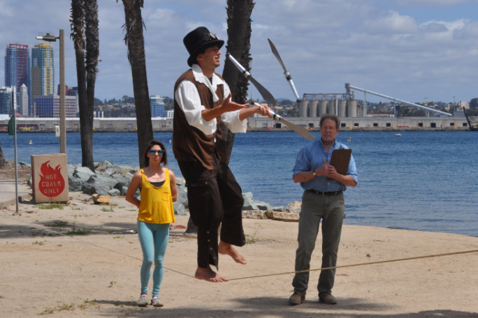 Daring circus performer juggles knives while walking a slackline ...